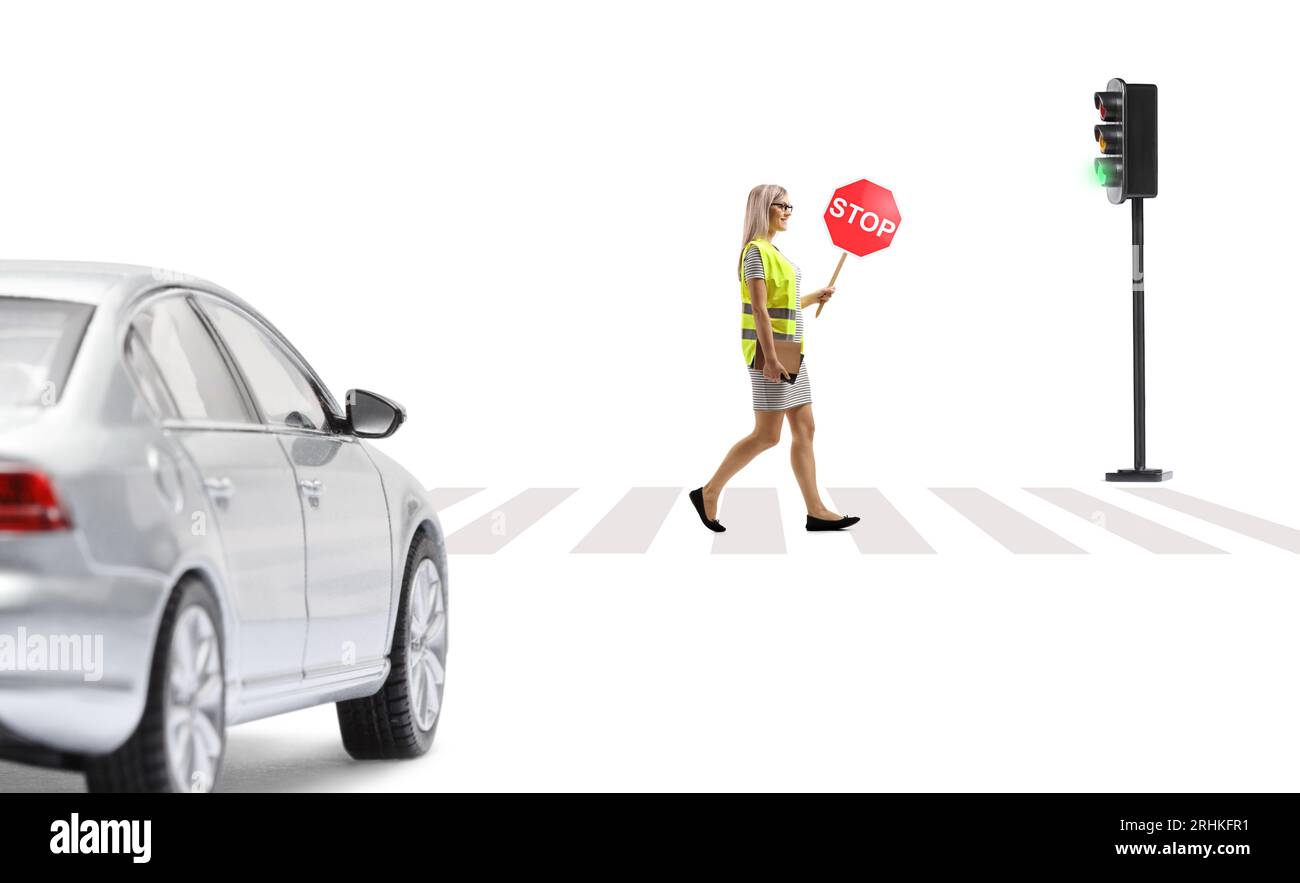 Woman with a stop sign and a safety vest crossing a street at a ...