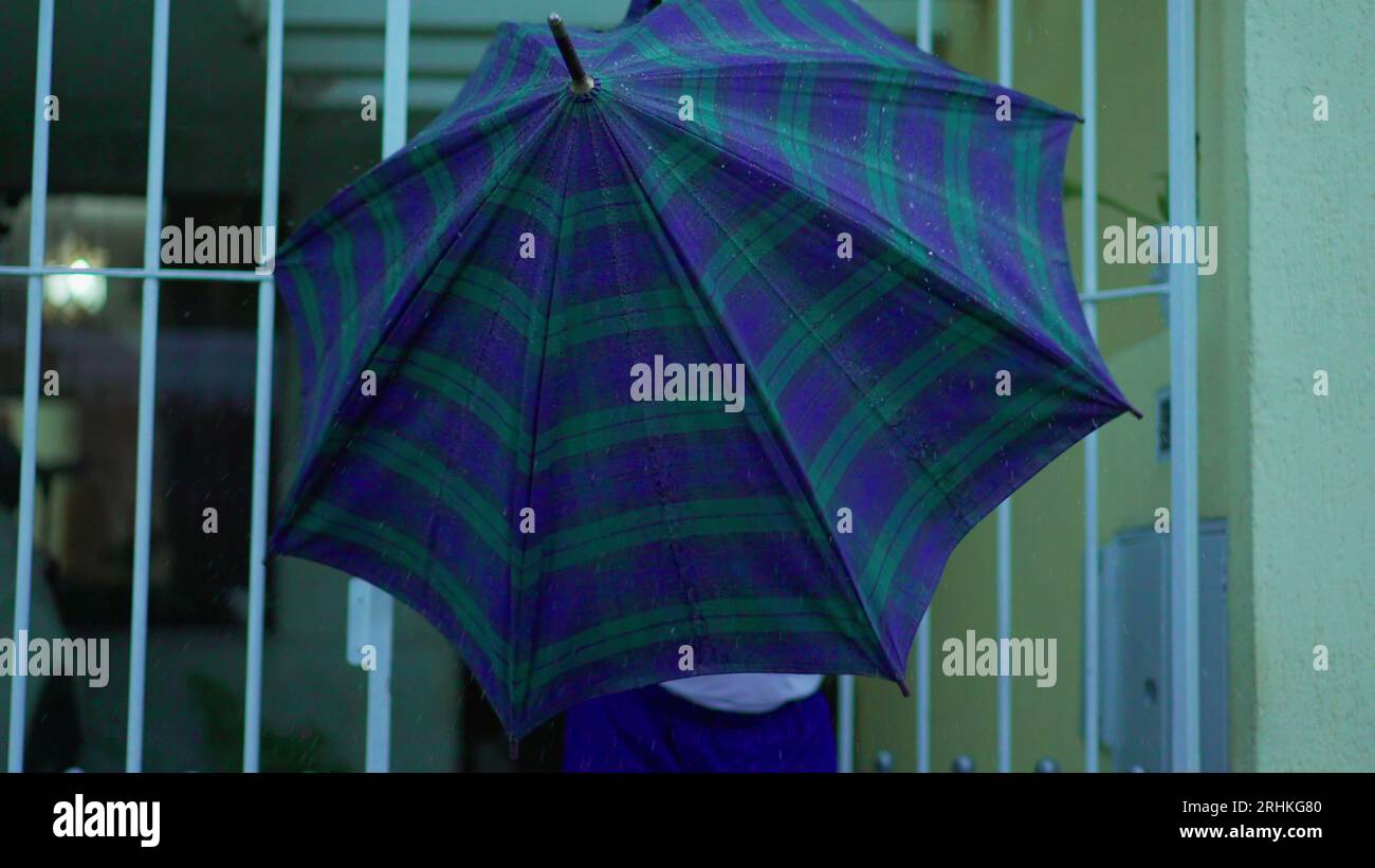 Senior man opening umbrella to protect from rain, steps out in the ...