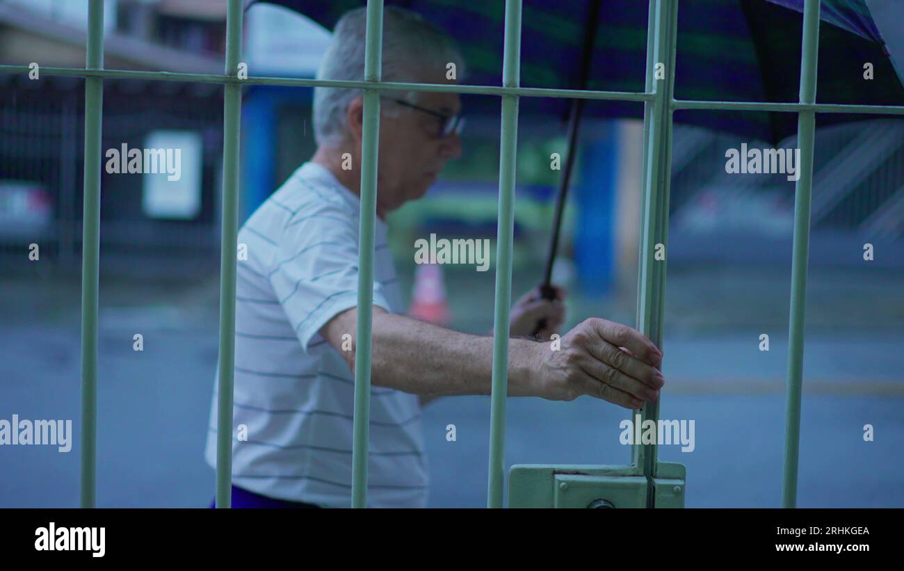 Senior man stepping out in the street during rainy evening, opening ...