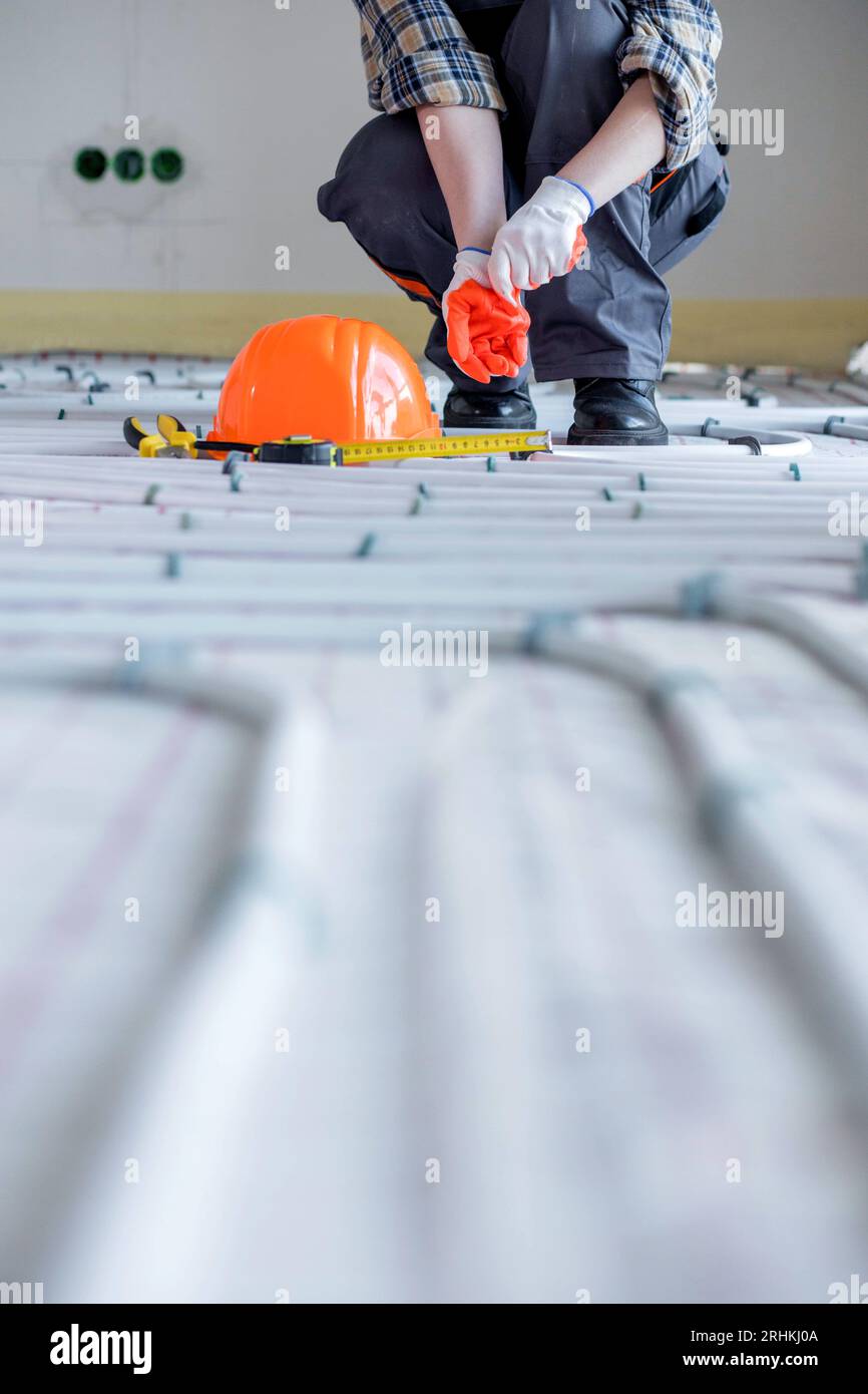 Worker near tools for repair hard hat, plier, glove on warm floor ...