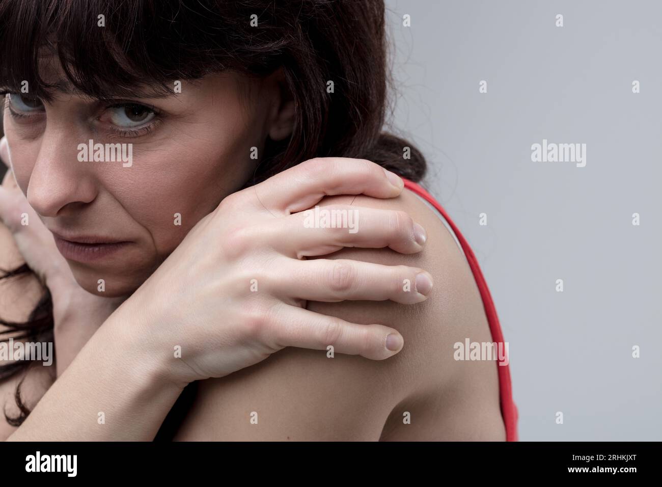 Woman hugging her shoulders in fear of further abuse and violence. She ...