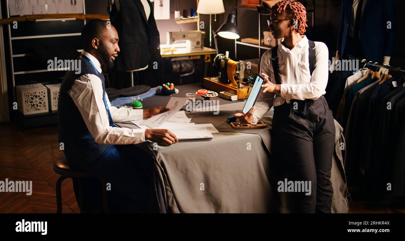 Tailors choosing design of clothes using modern fashion sketches in ...
