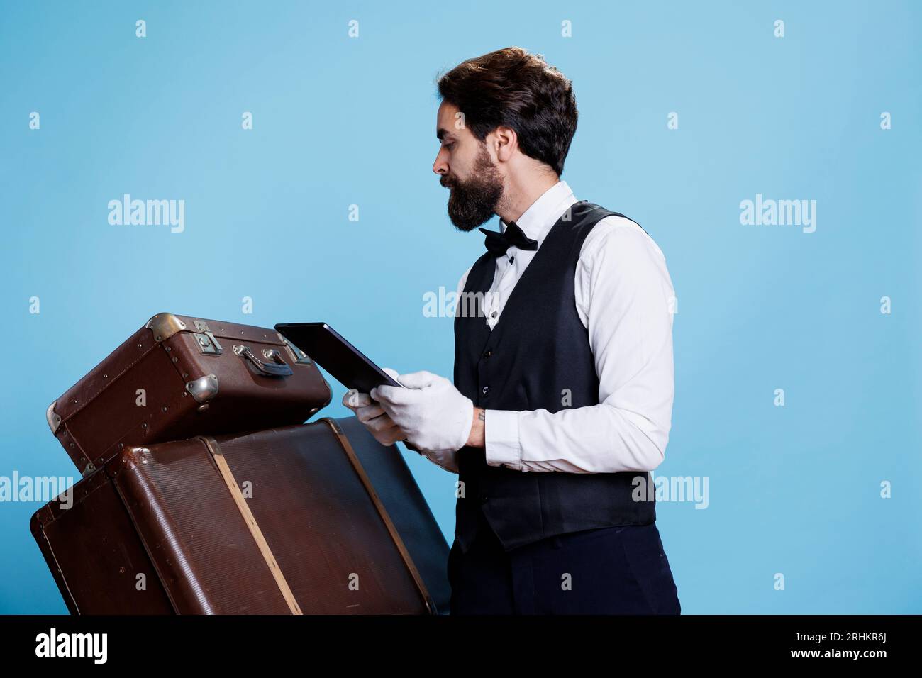 Hotel concierge counting trolley bags and checking tablet with list of ...