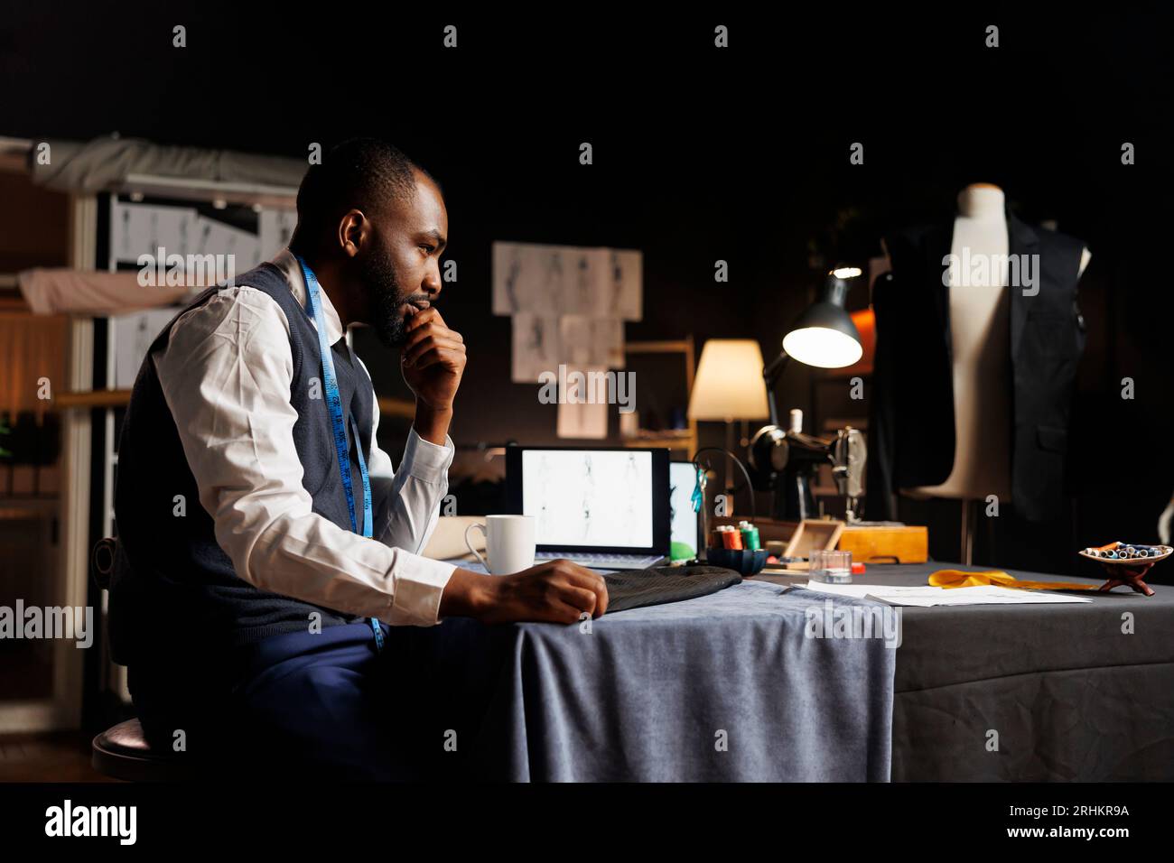 Experienced couturier overthinking in atelier shop workspace, working ...