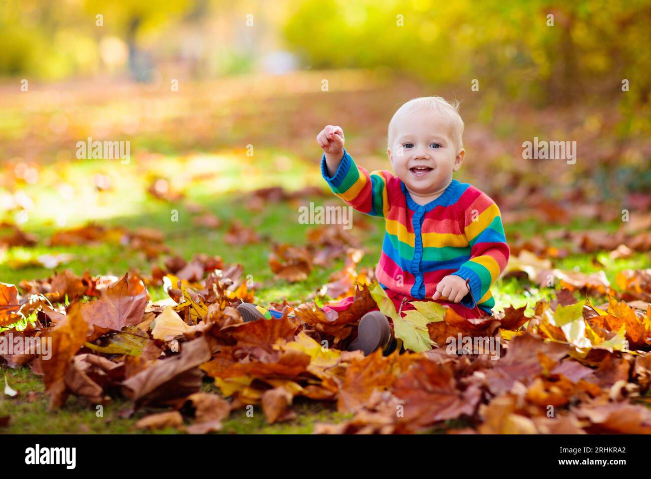 Kids play in autumn park. Children throwing yellow and red leaves ...