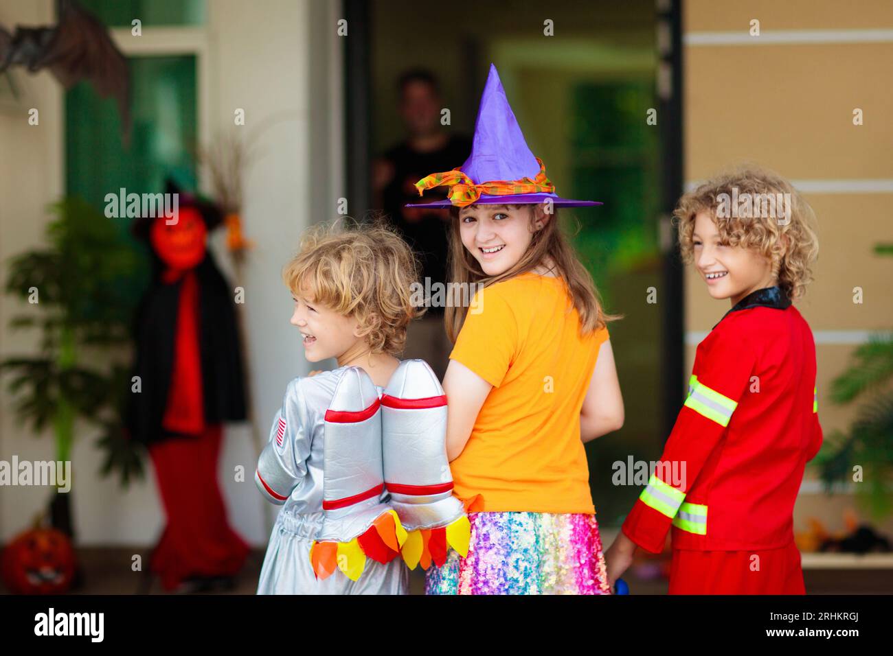Kids trick or treat on Halloween night. Dressed up children at ...