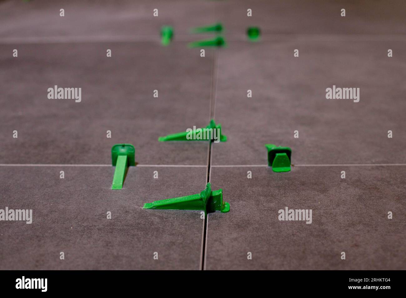 Tile levelling system, four plastic green clips with wedges. Close-up ...