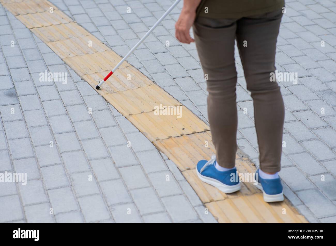 Close-up of the legs of an elderly blind woman with a cane at a tactile ...