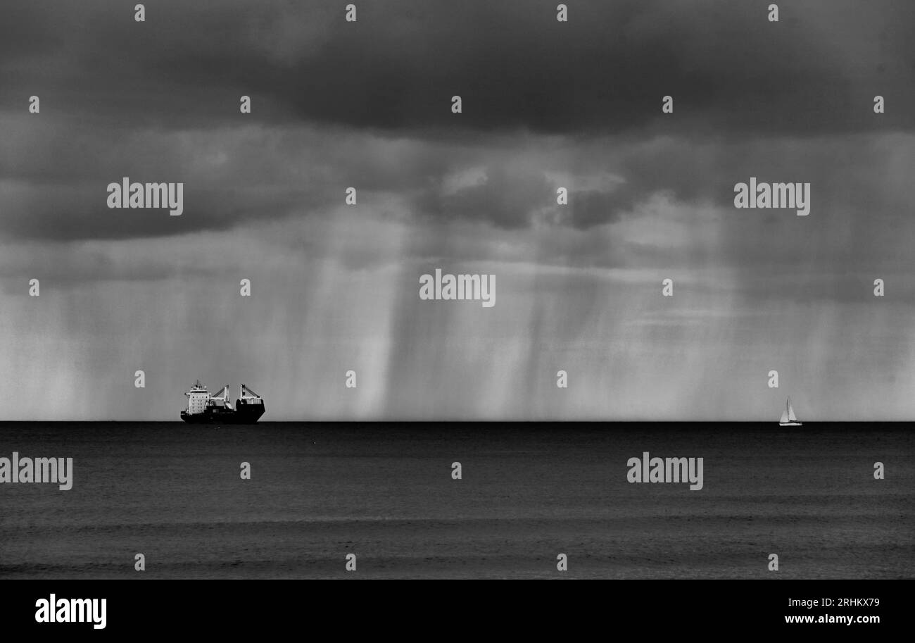 Cargo ship and yacht sailing through a North East squall in the North ...
