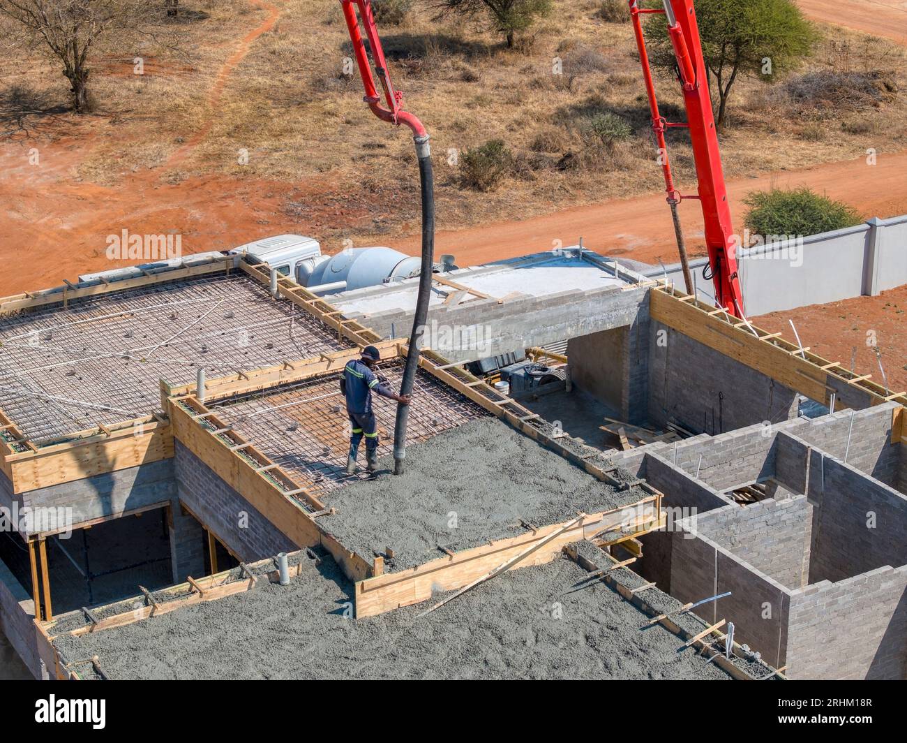 african construction workers in town at the construction site using a boom concrete pump to fill ...