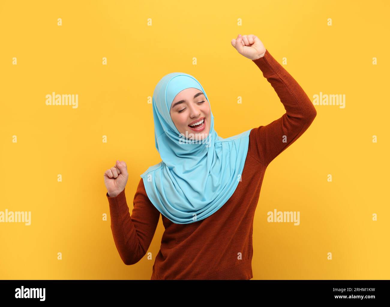 Muslim woman in hijab dancing on orange background Stock Photo - Alamy