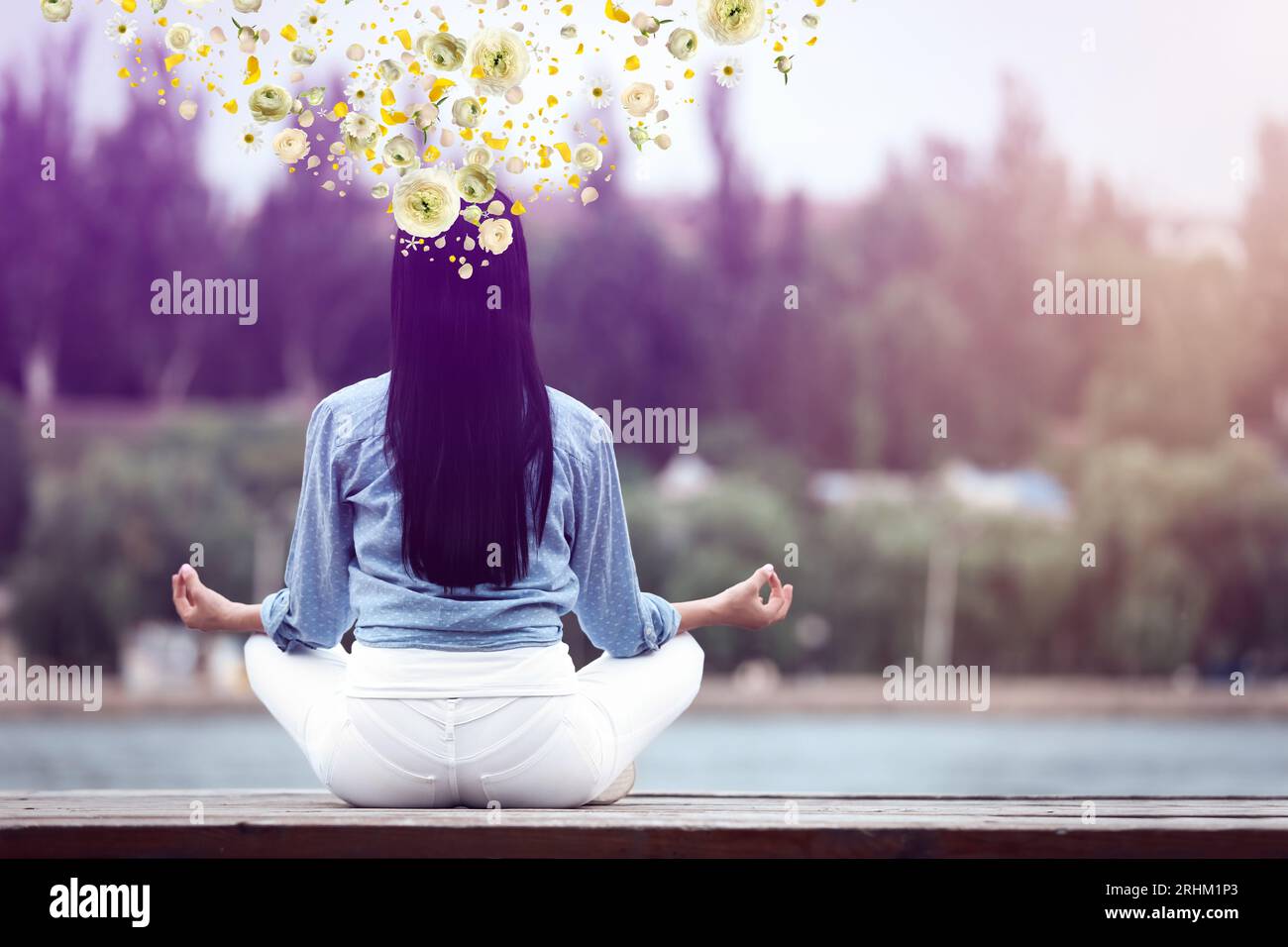 Woman meditating near river, back view. Flowers near her head ...