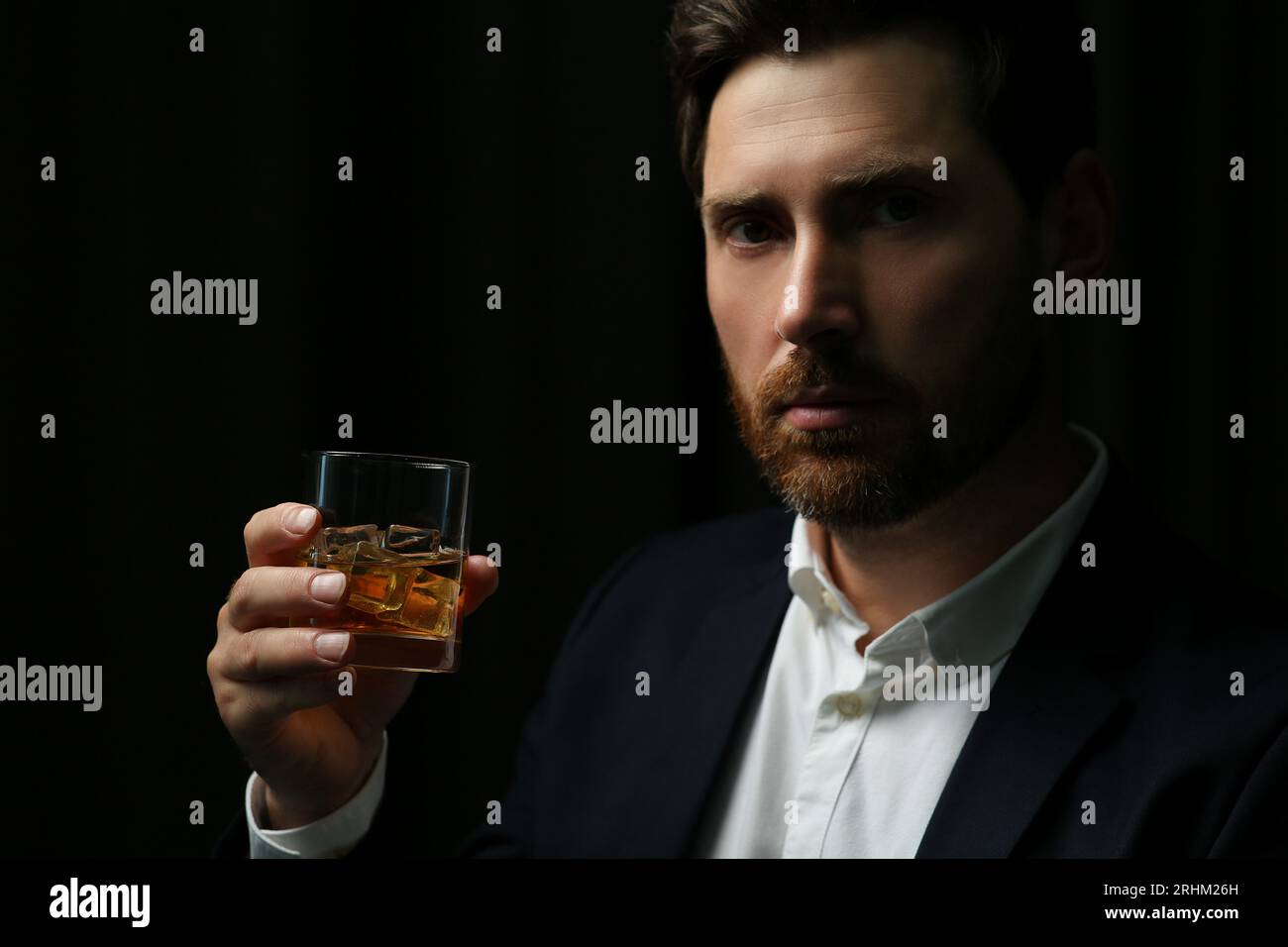 Handsome man in suit holding glass of whiskey on black background Stock ...