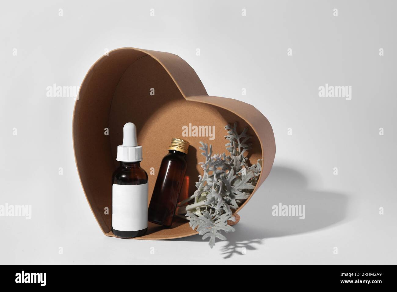 Heart shaped box with cosmetic products and silver leaves on white ...