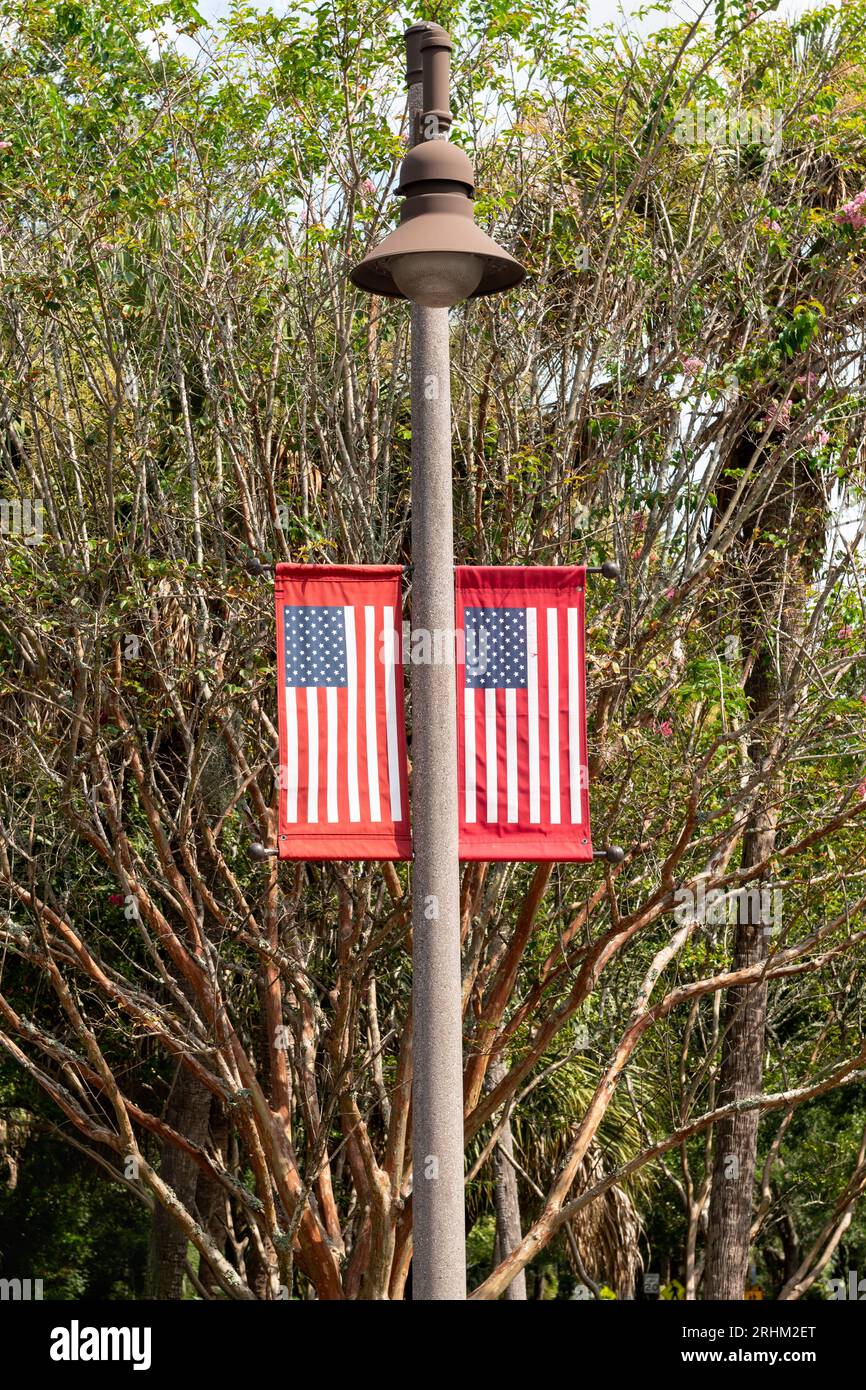 US flags under a street light pole with trees in the background Stock ...