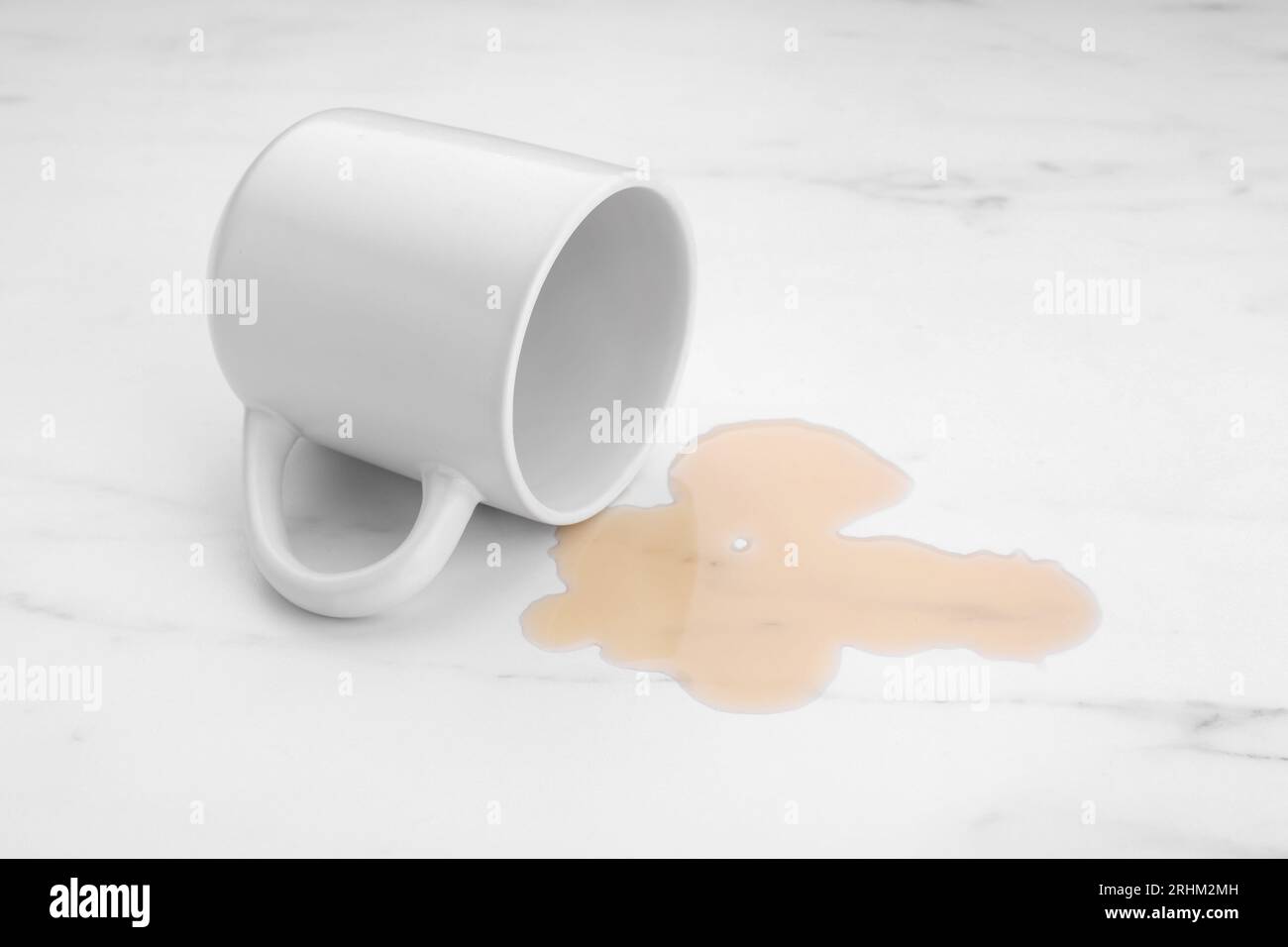Puddle of liquid and overturned mug on white marble table Stock Photo ...