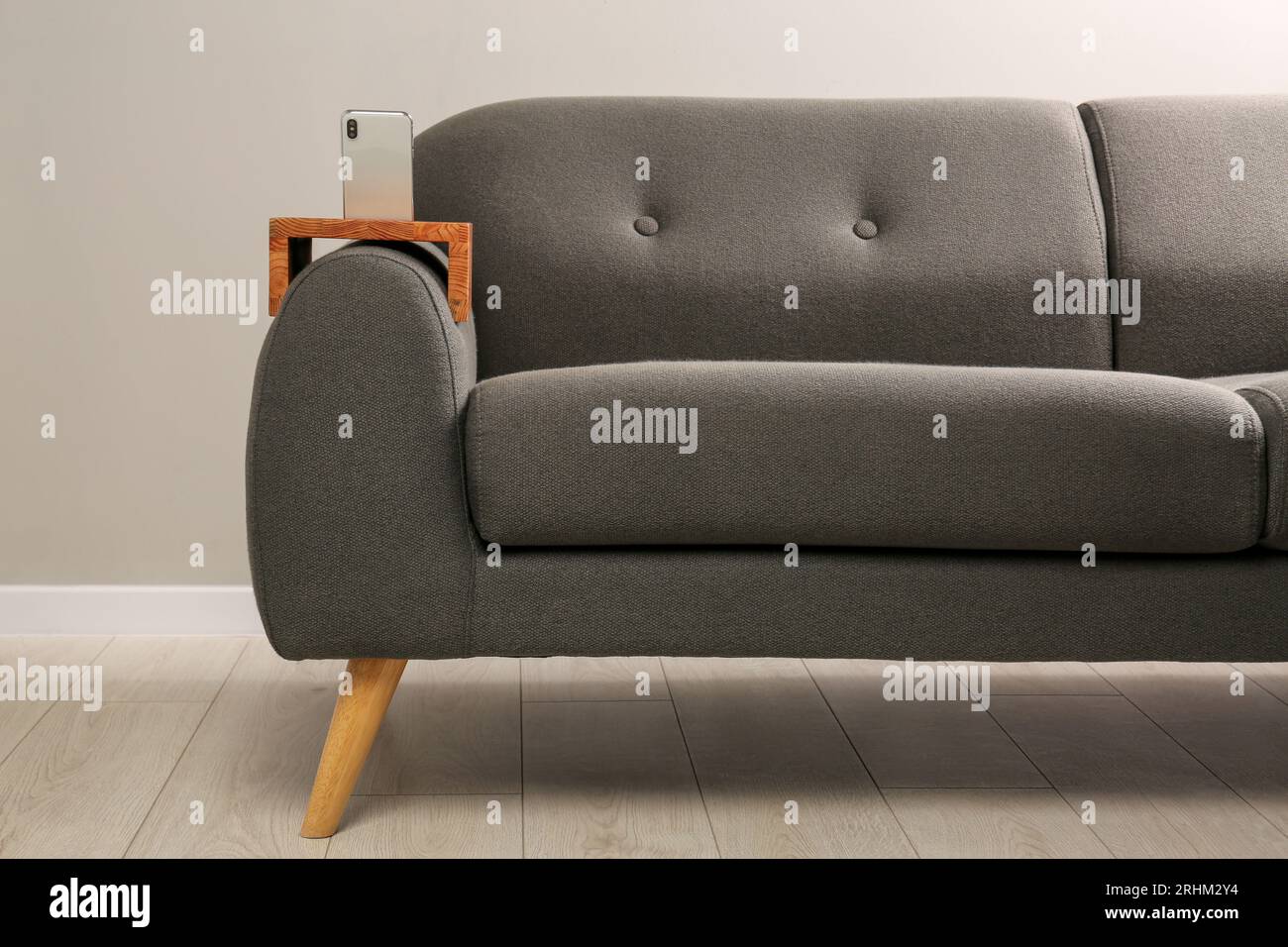 Smartphone on sofa with wooden armrest table in room. Interior element ...