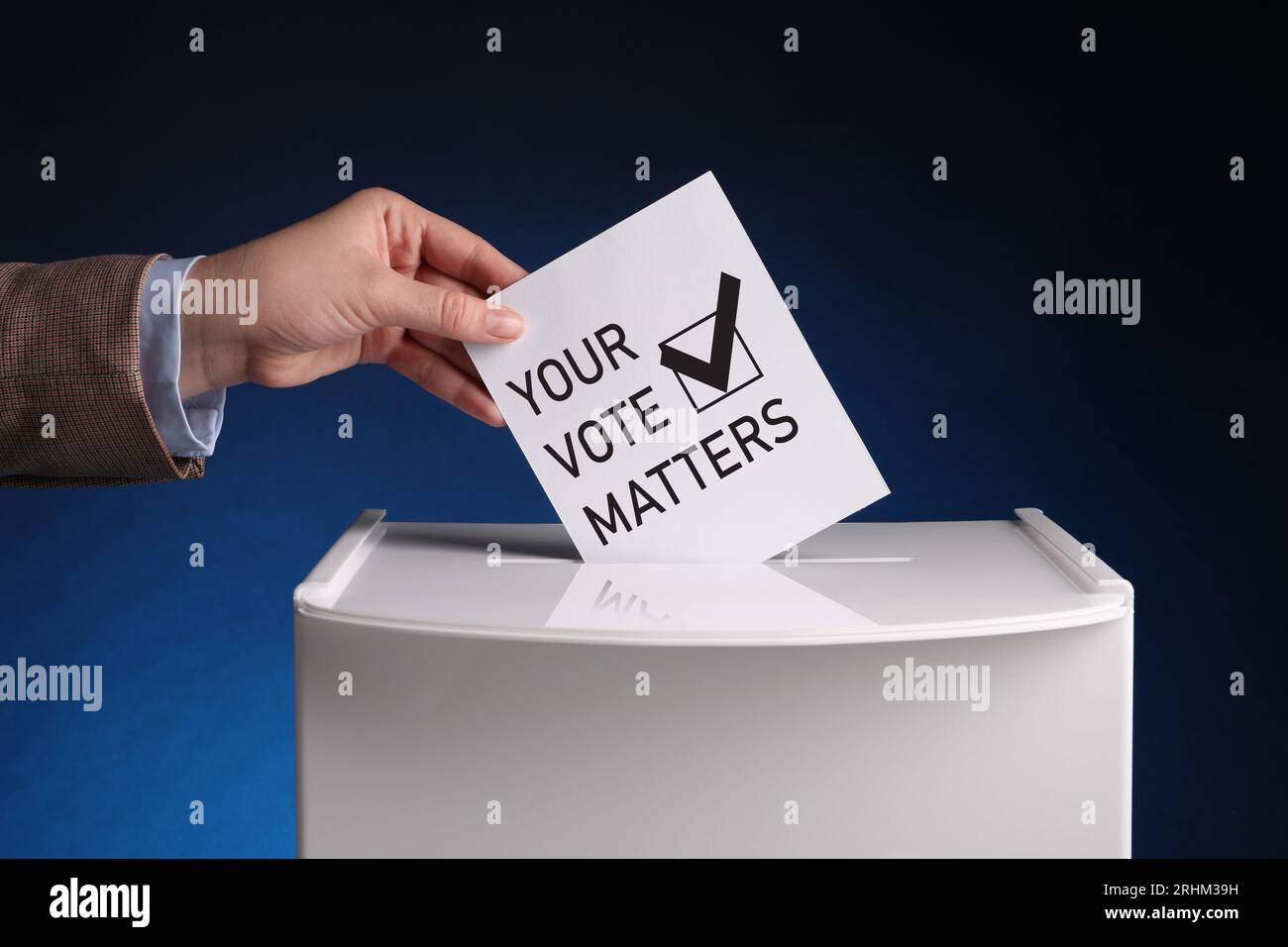 Woman putting paper with text Your Vote Matters and tick into ballot ...
