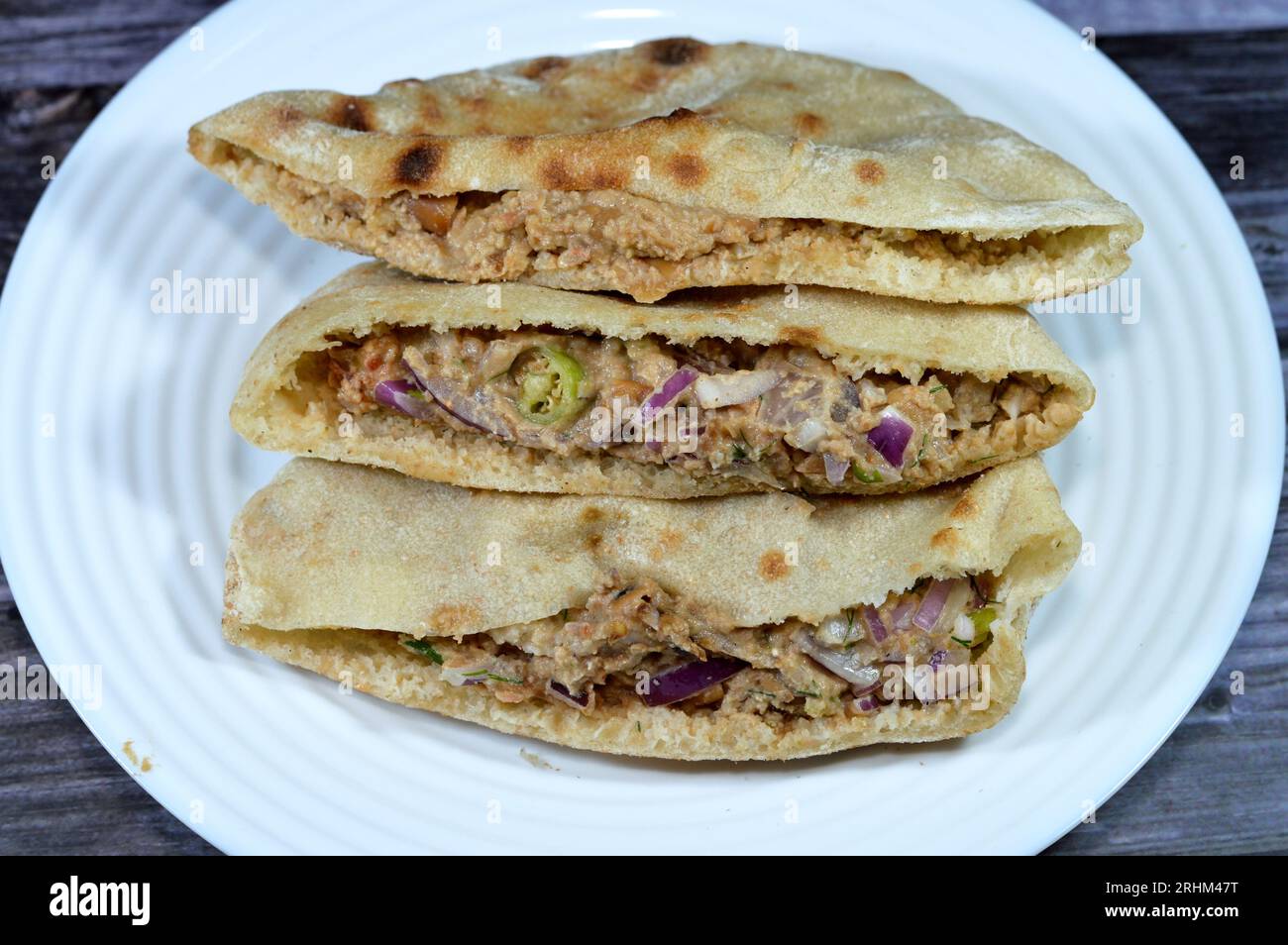 A flat bread with mashed fava beans mixed with oil, sesame tahini ...