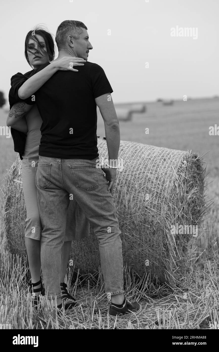A young couple of beautiful people have fun in the field near round ...
