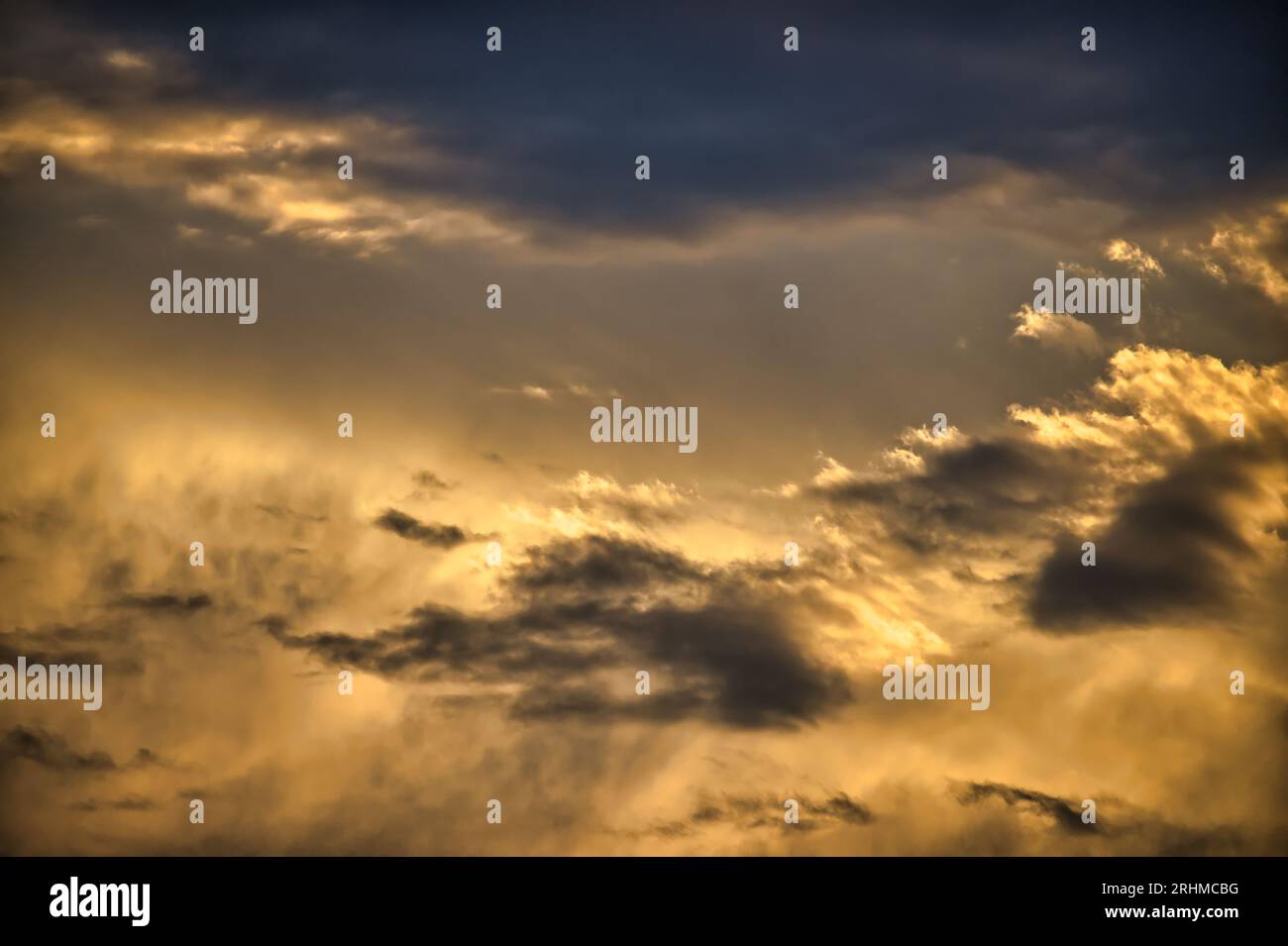 Sky with clouds which carry a dominant golden hue indicative a sunrise ...