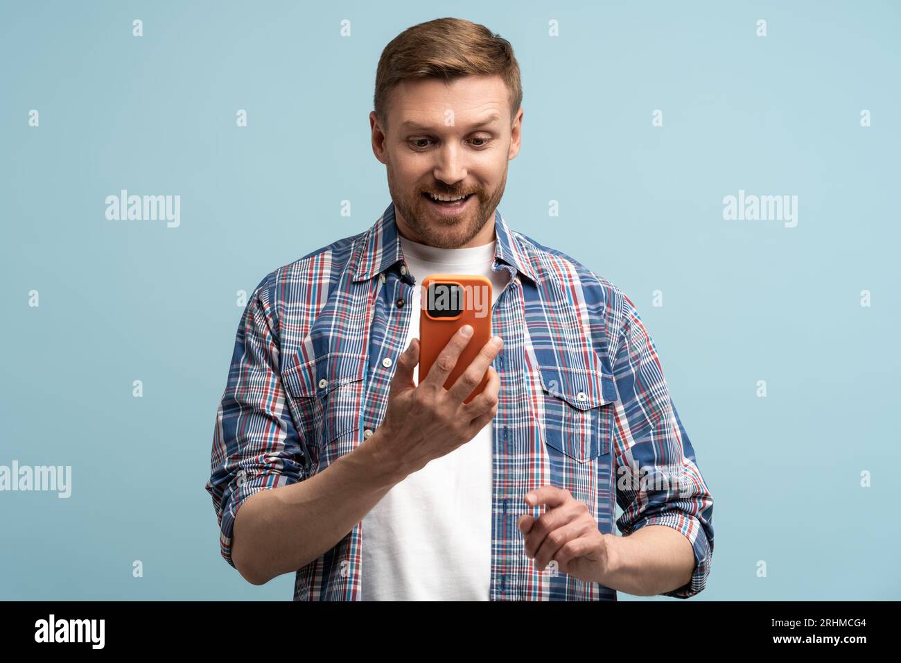 Man with smartphone smiles happily, looks at screen. Good news ...