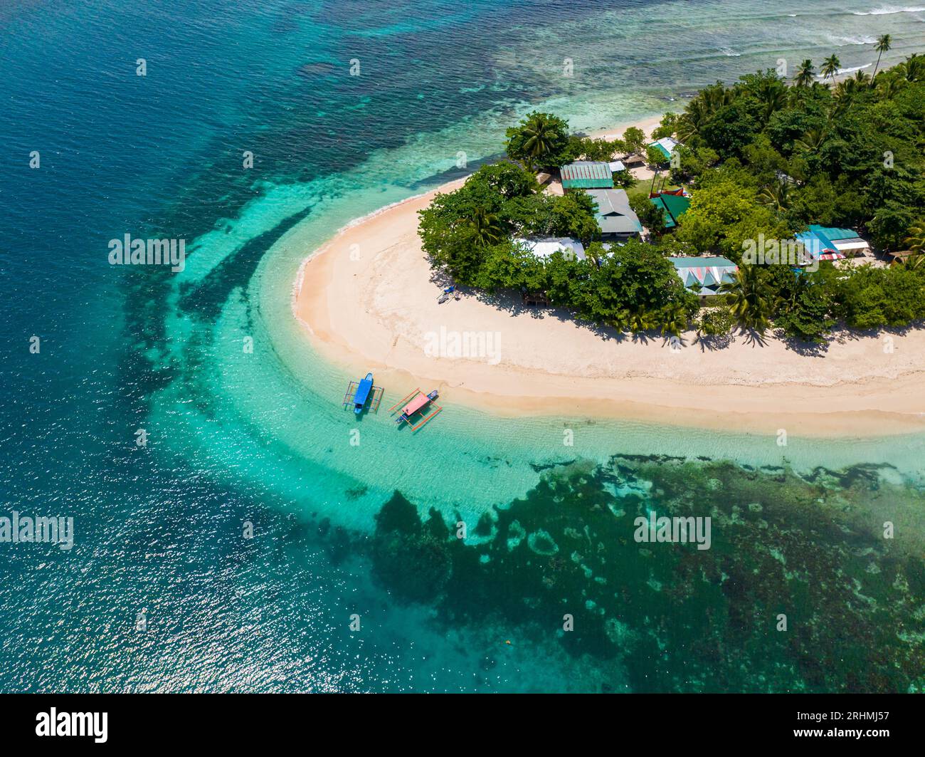 Shiny white sandy beach with two boats on turquoise water and corals ...