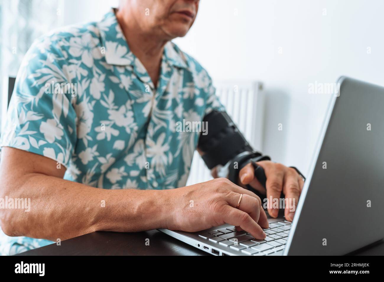 Man with adjustable articulated elbow orthosis typing on laptop ...