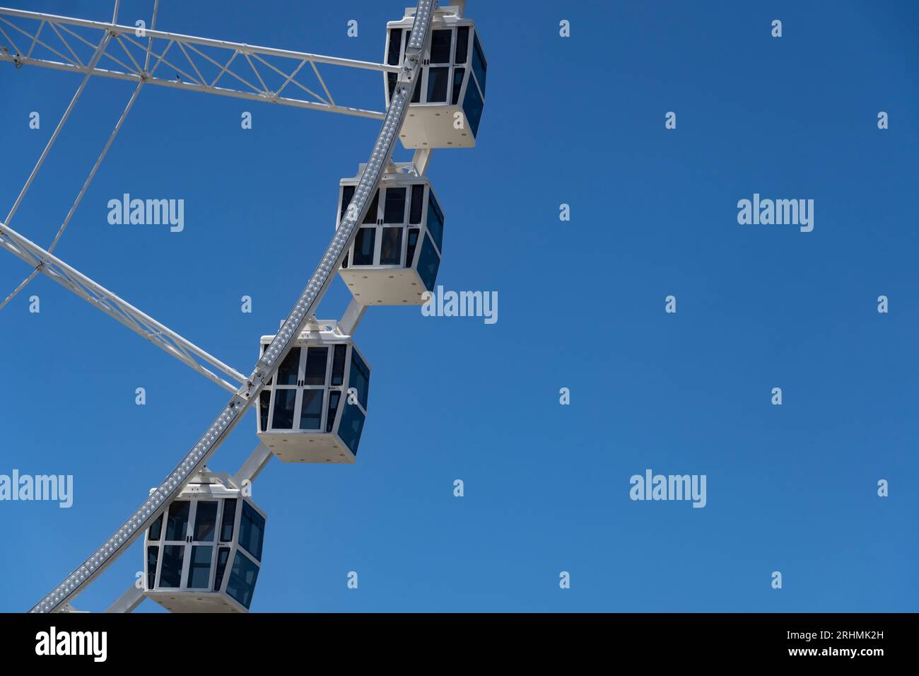 Close-up details of ferris wheel on clear blue sky background, with ...