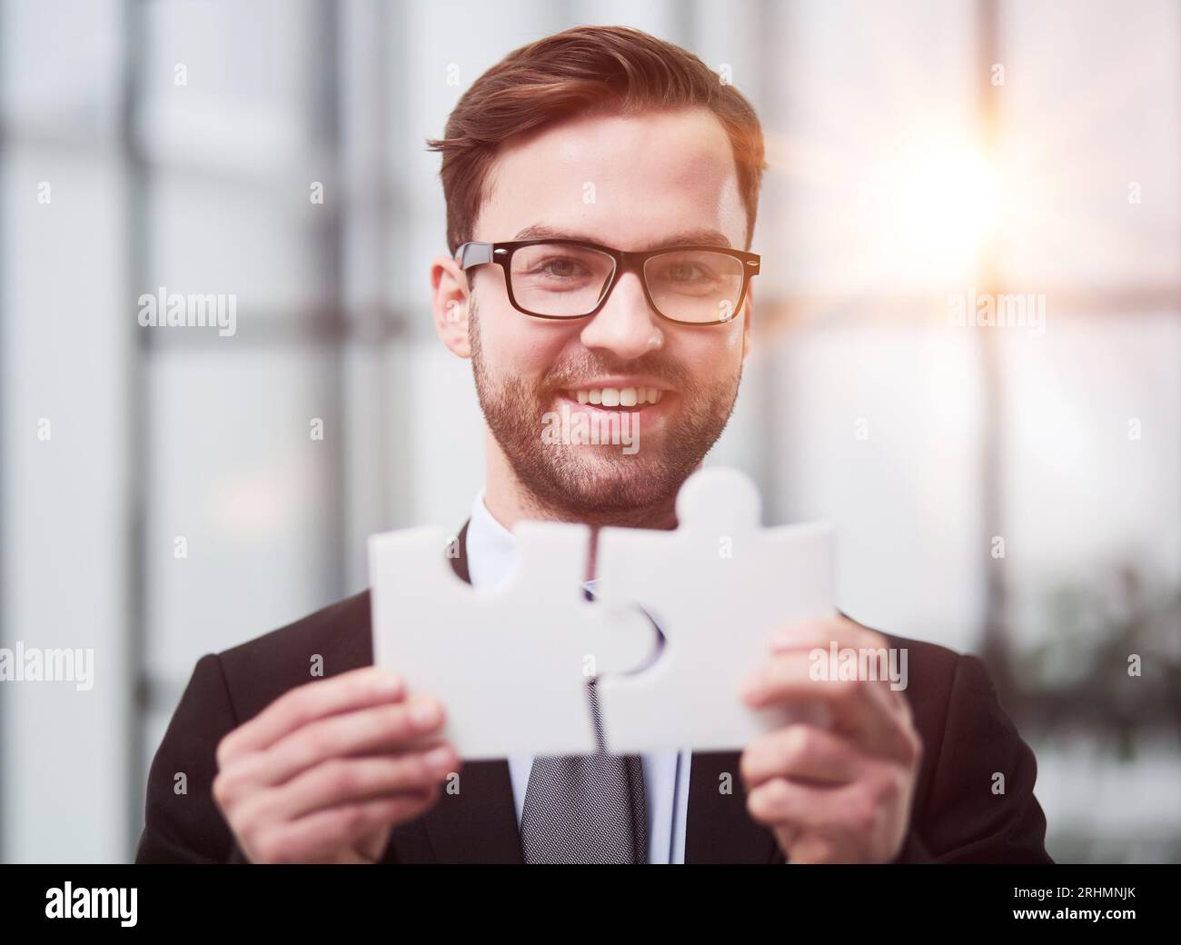 Portrait of an optimistic businessman holding puzzle pieces, solving ...