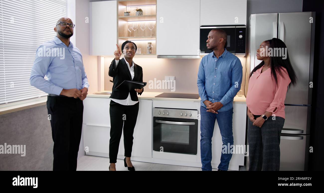 Real Estate Agent Showing House Kitchen To A Young Couple Stock Photo ...