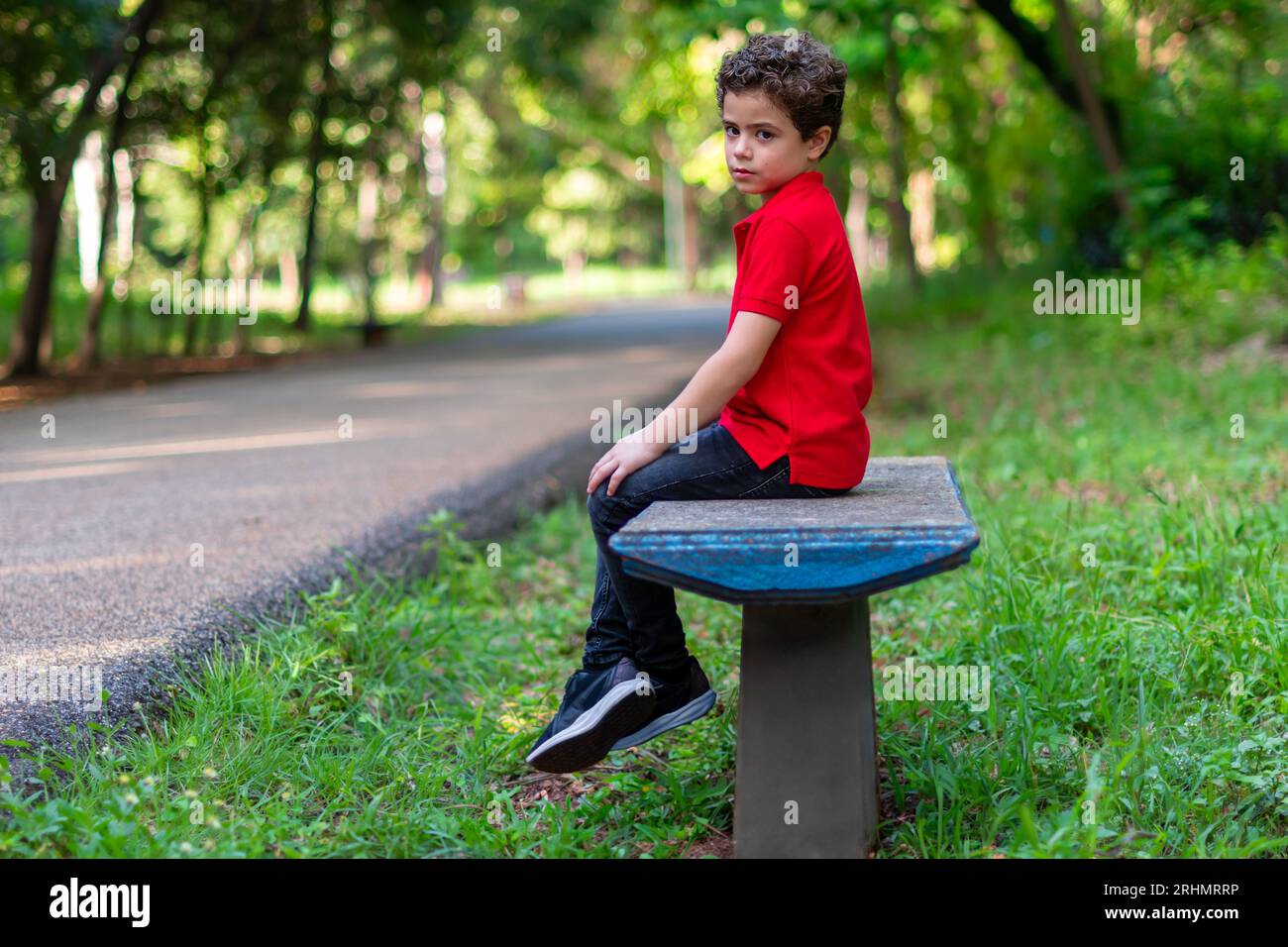 Boy sitting on a park bench Stock Photo - Alamy
