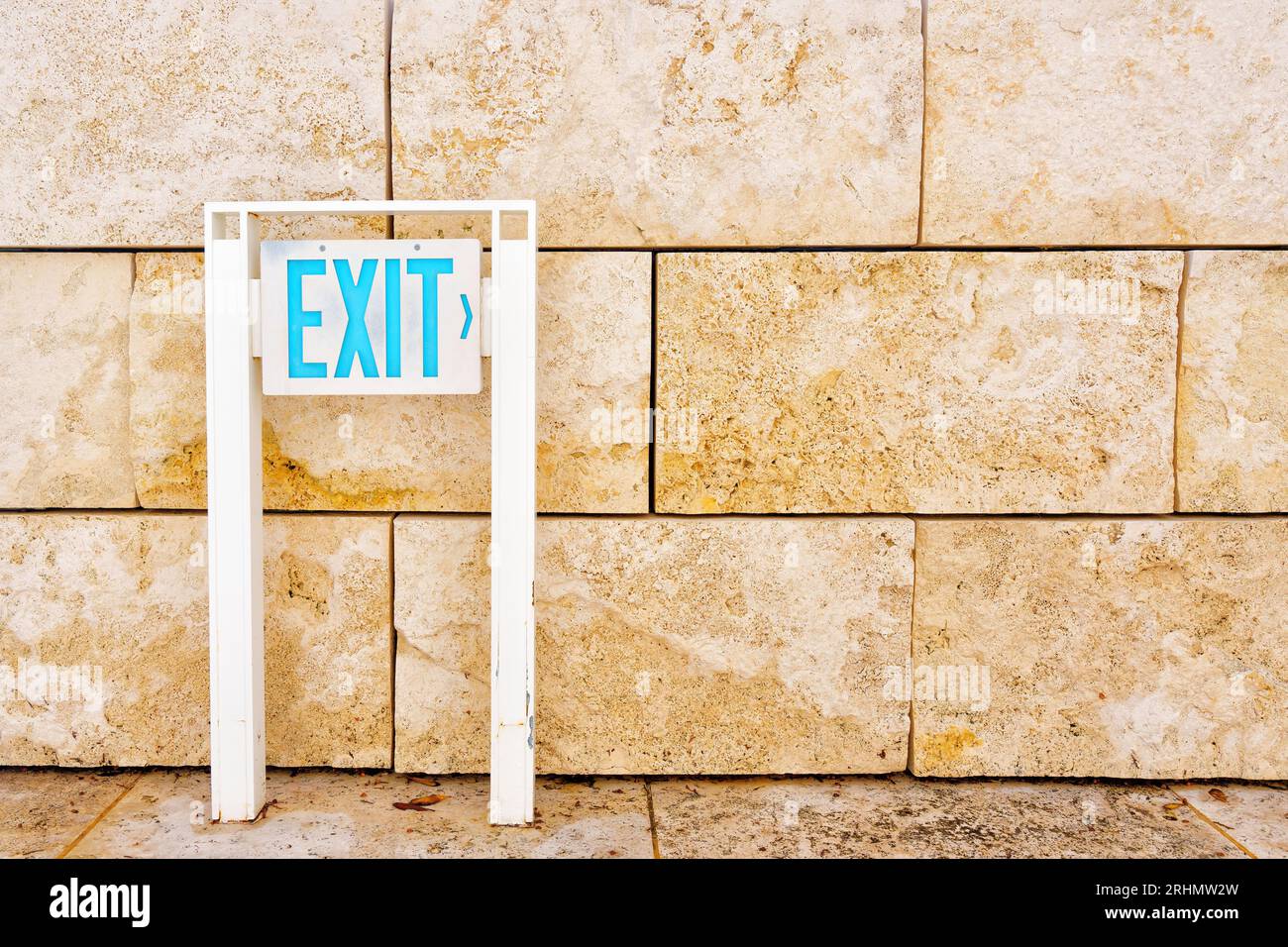 EXIT sign placed next to a wall constructed from sturdy stone slabs ...