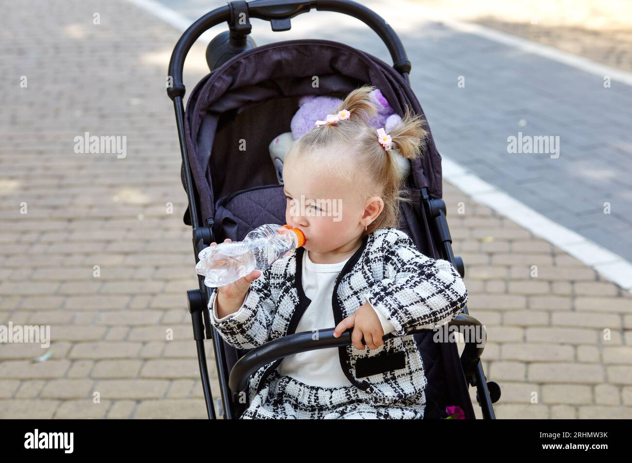 Baby in stroller on a walk in summer city park. Adorable little girl ...