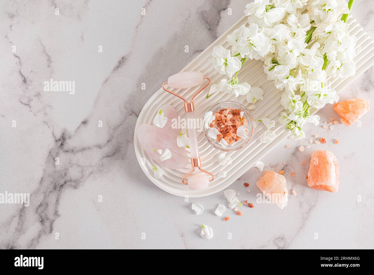Quartz massage roller and gua sha scraper on a white arch podium ...