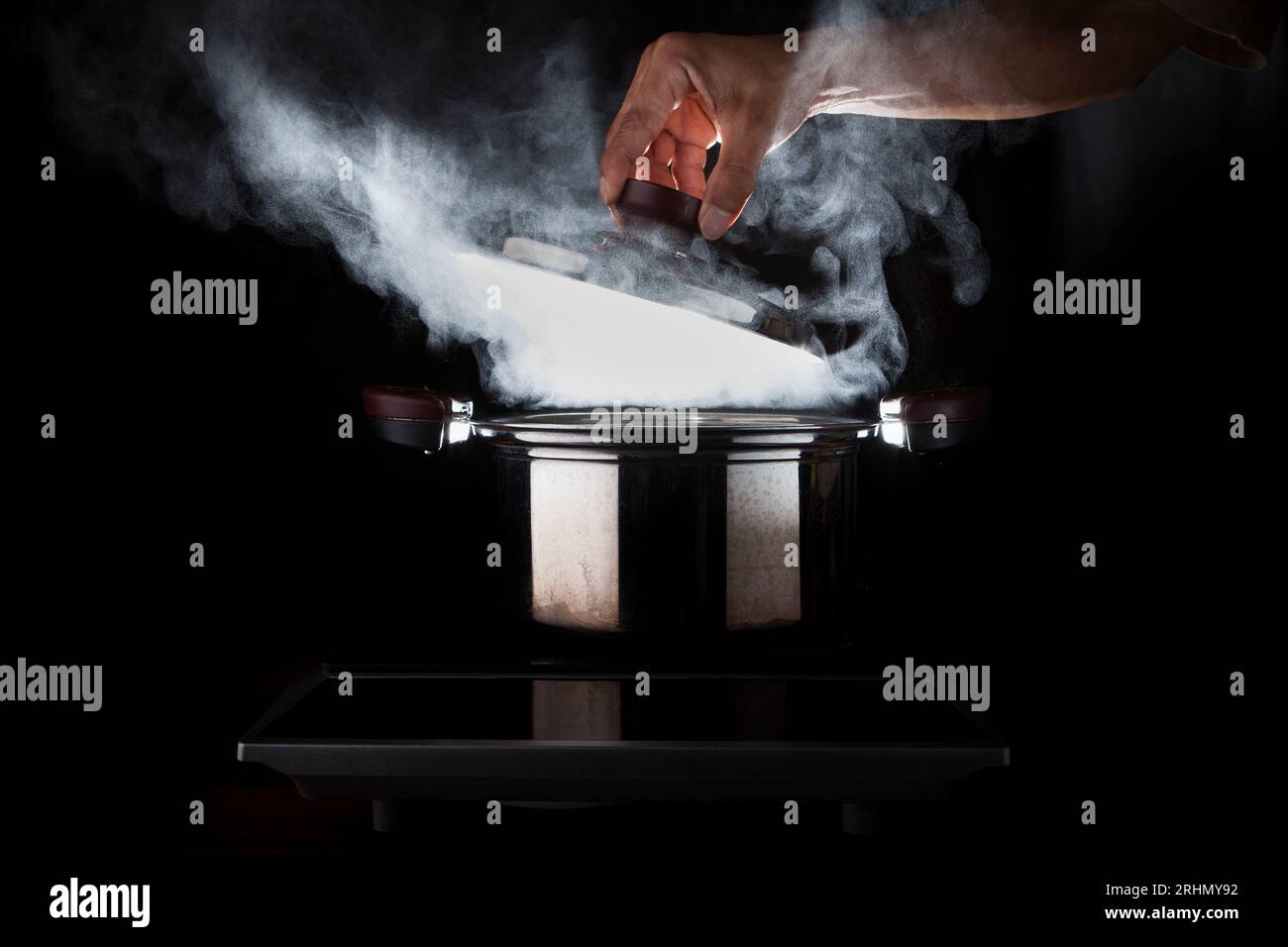hand open hot boil pot on magnetic oven against black background Stock ...