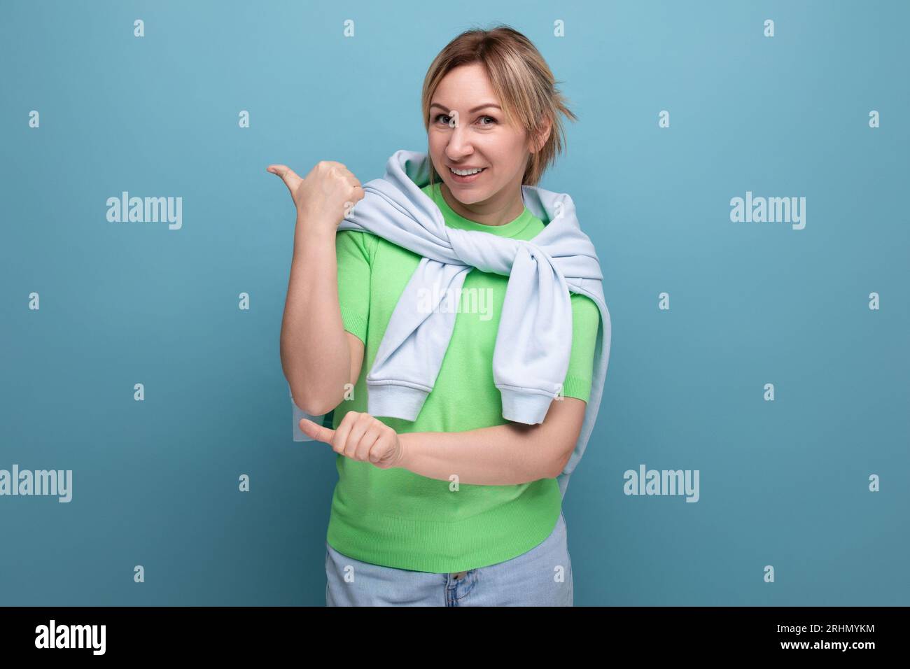portrait of a positive bright young woman in a casual outfit on a blue ...