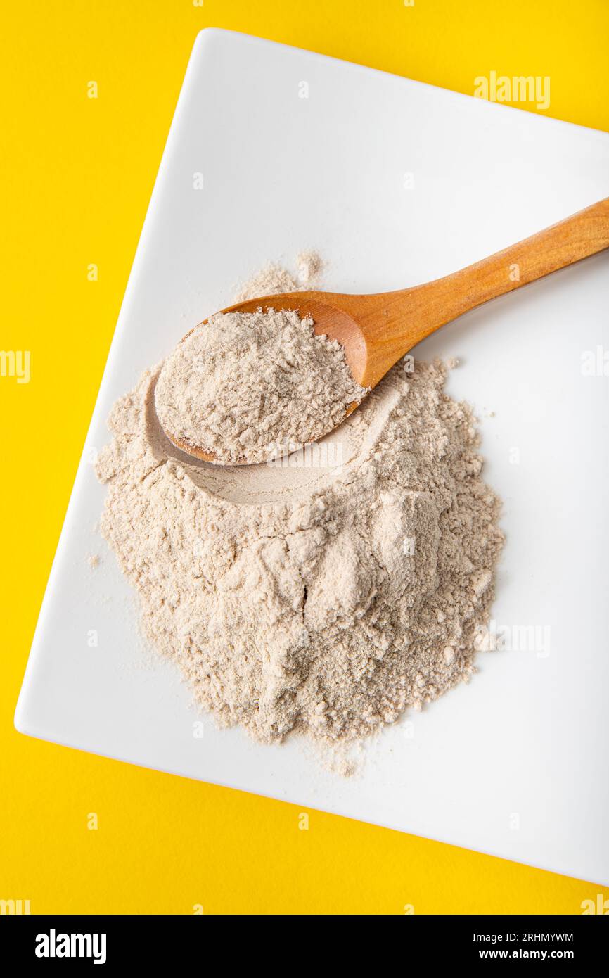 Psyllium husk flour powder on white plate and wooden spoon indoors at ...