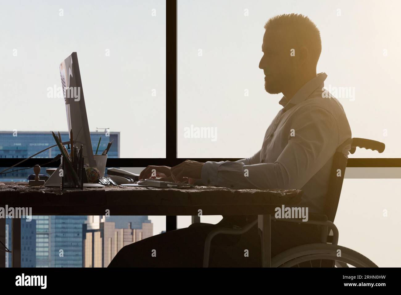 Disabled Businessman Sitting In Wheelchair Using Computer At Workplace Stock Photo - Alamy