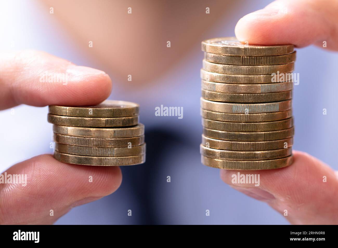 Man Holding Two Coin Stacks To Compare Stock Photo - Alamy