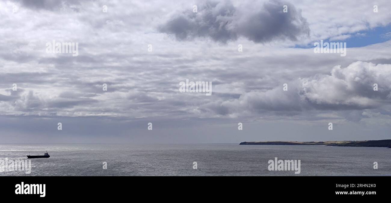 Cargo ship in the open stormy sea. With heavy rainy sky background ...