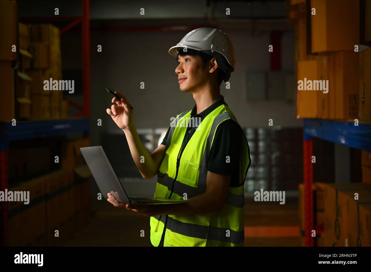 Male worker wearing safety vest and hard hat holding laptop checking ...