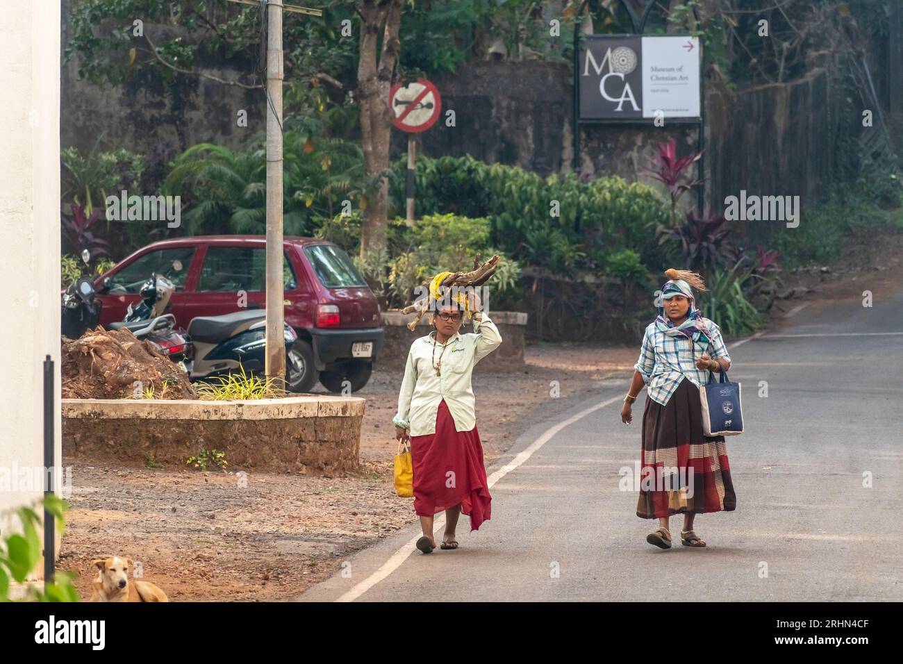 Old Goa, India - January 2023: Two Goan women walking with branches of ...
