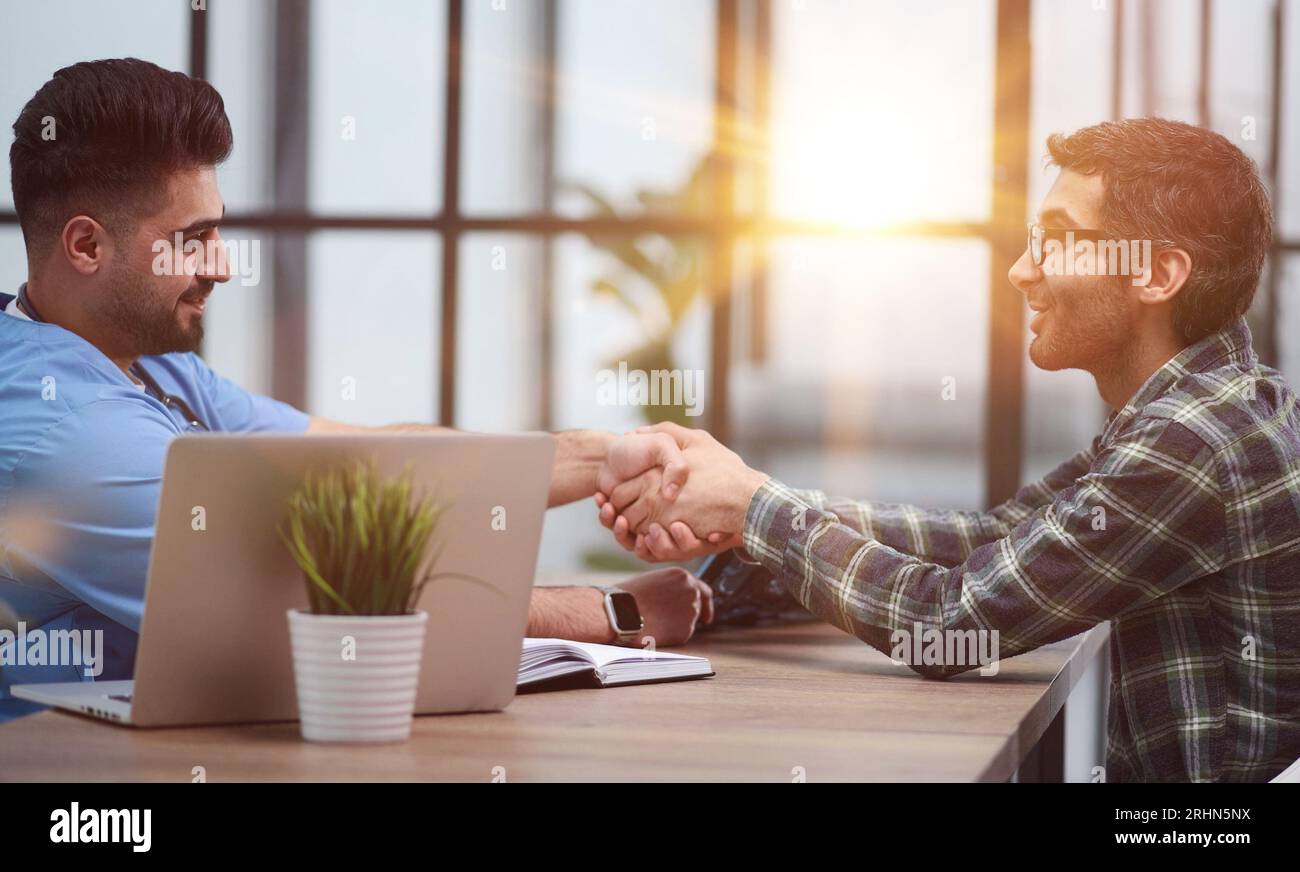 Nice doctor shaking hands with the patient Stock Photo - Alamy