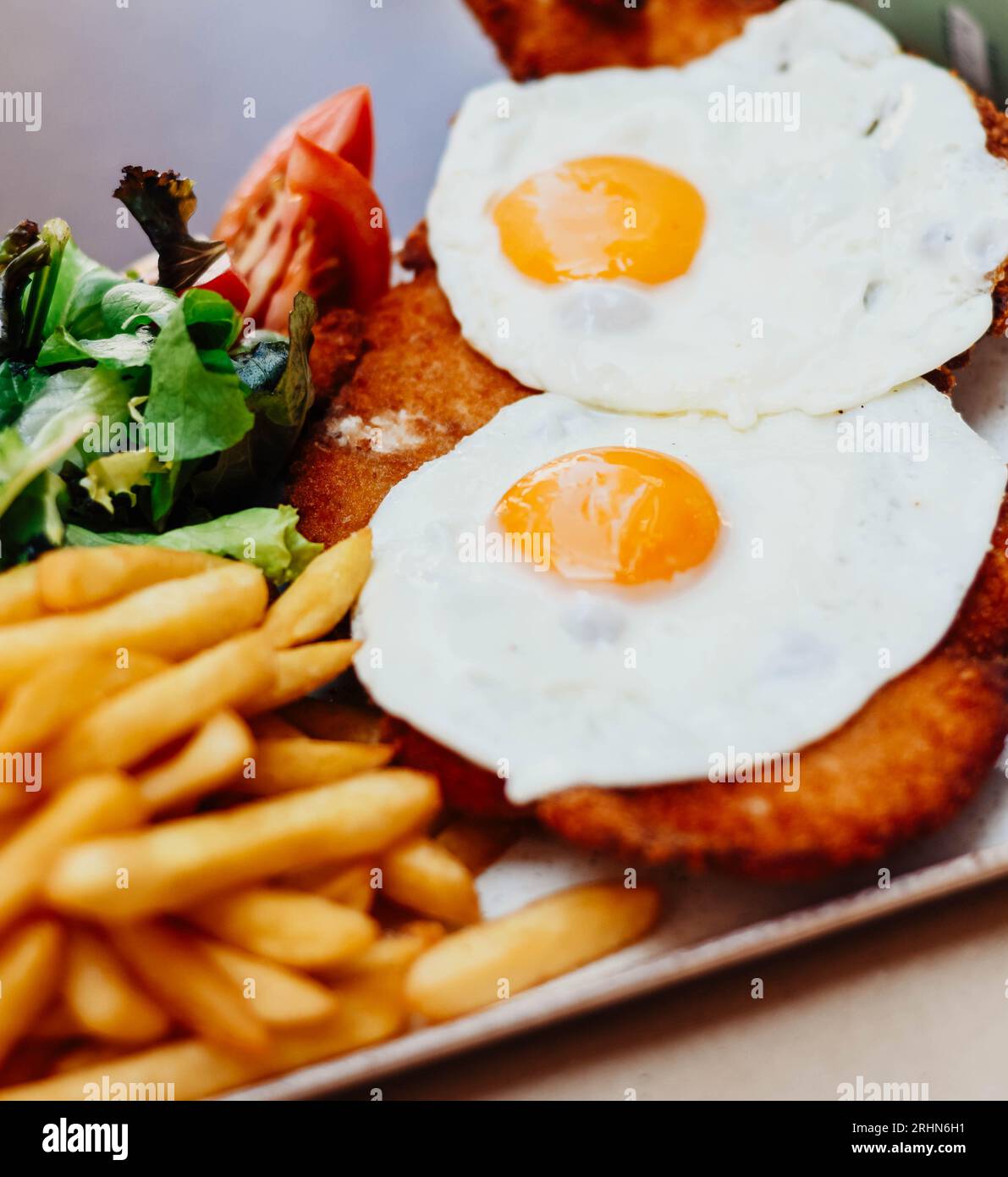 Delicious breaded beef dish with ham, cheese, fried eggs Stock Photo ...