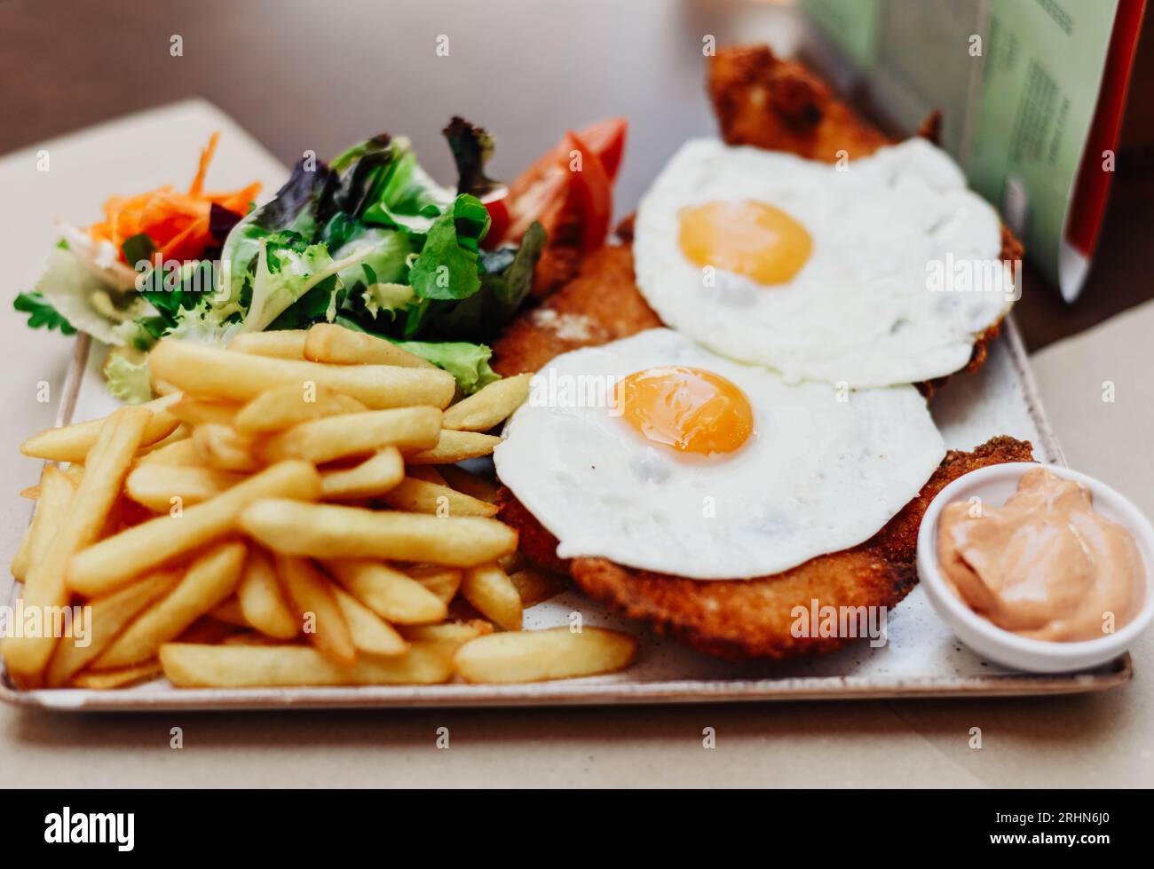 Delicious breaded beef dish with ham, cheese, fried eggs Stock Photo ...