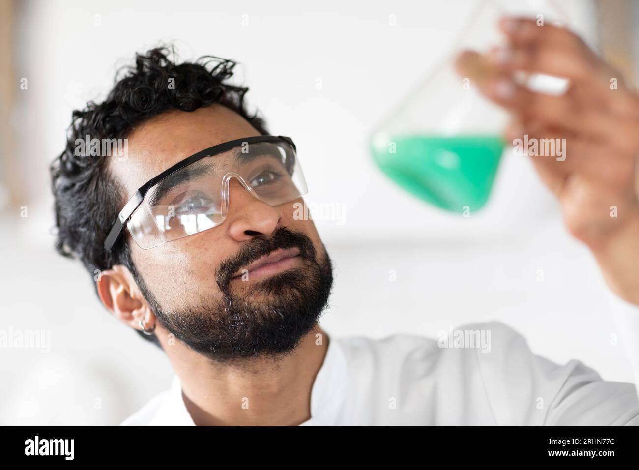 scientist male with beard looking to a sample in flask Stock Photo - Alamy