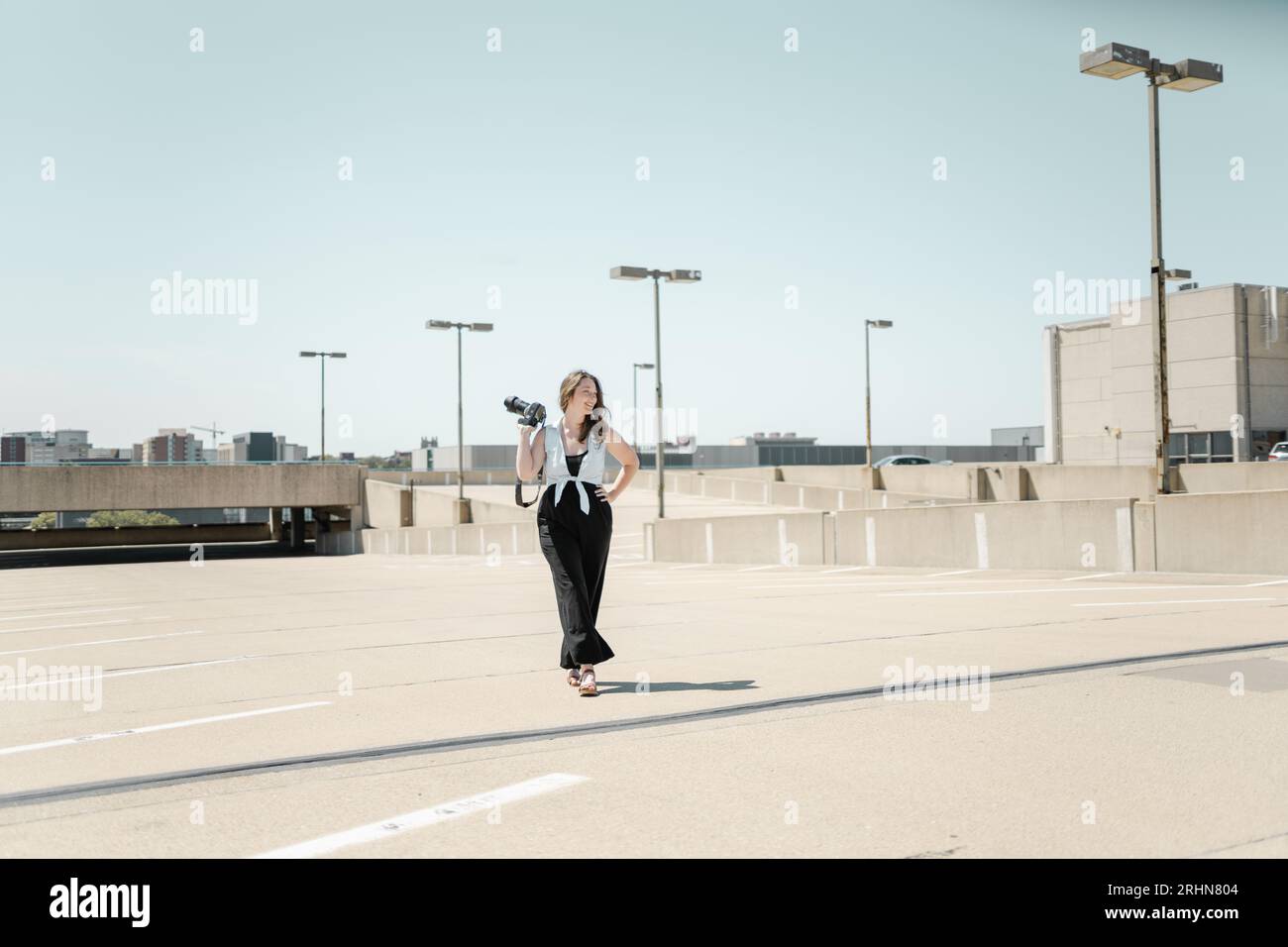 A woman walking through a parking garage holding a digital camera Stock ...