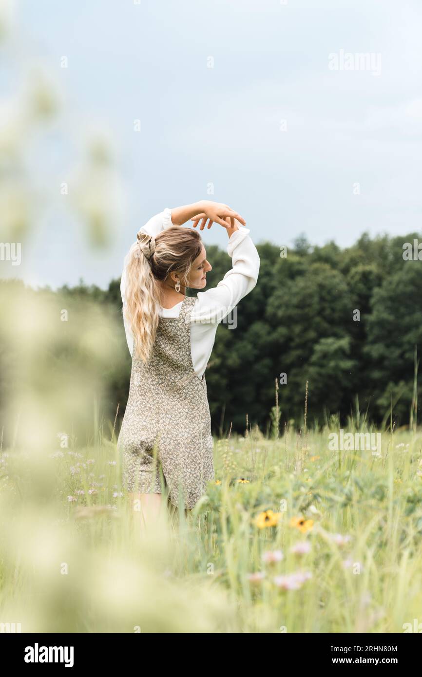 A woman in a floral jumpsuit dancing in a field of grass Stock Photo ...