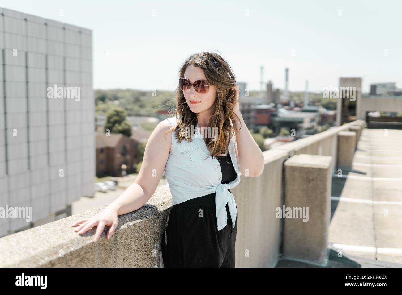A woman running her fingers through her hair on a parking ramp rooftop ...